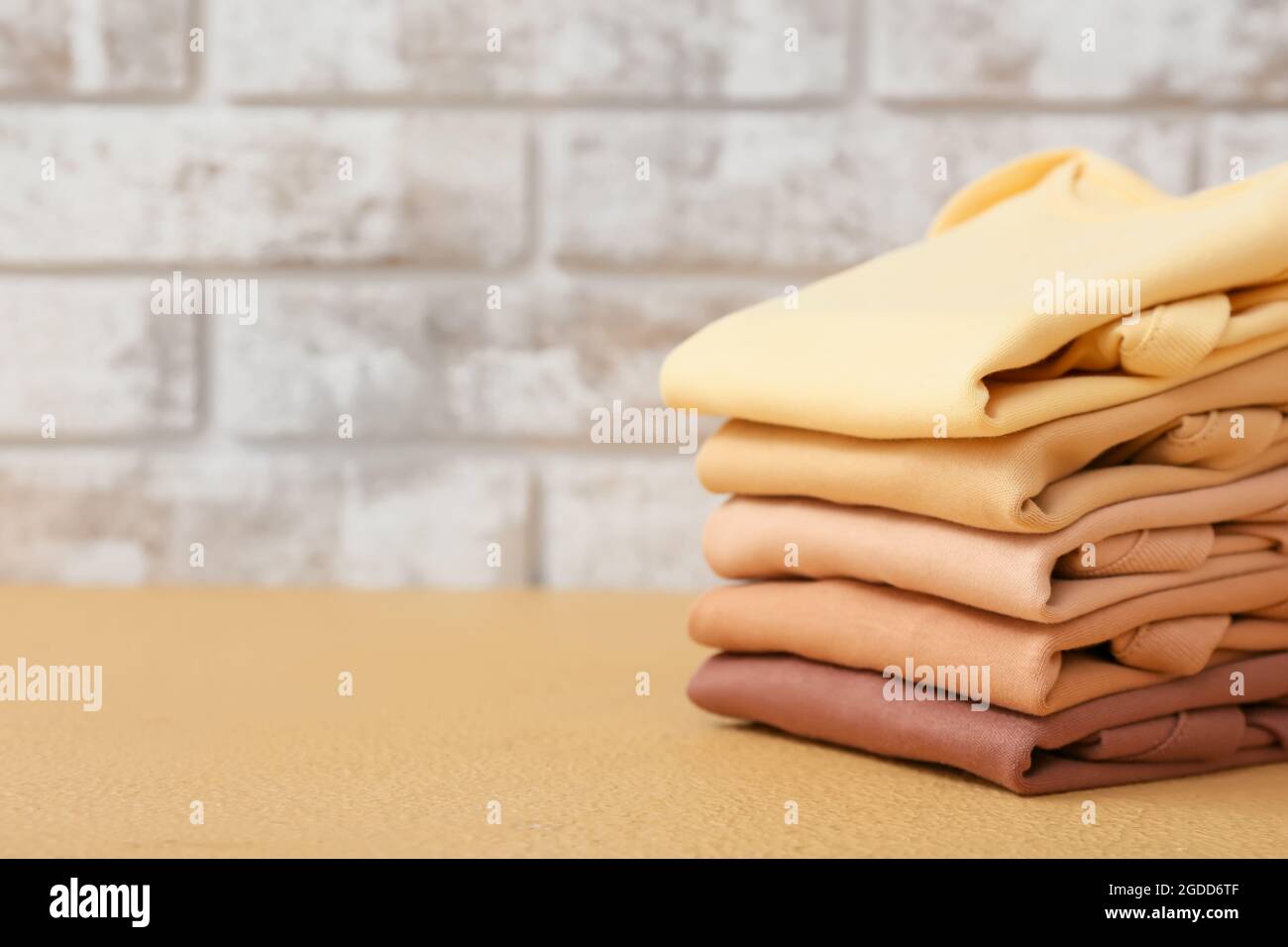 Stack of baby clothes on table against brick wall Stock Photo - Alamy