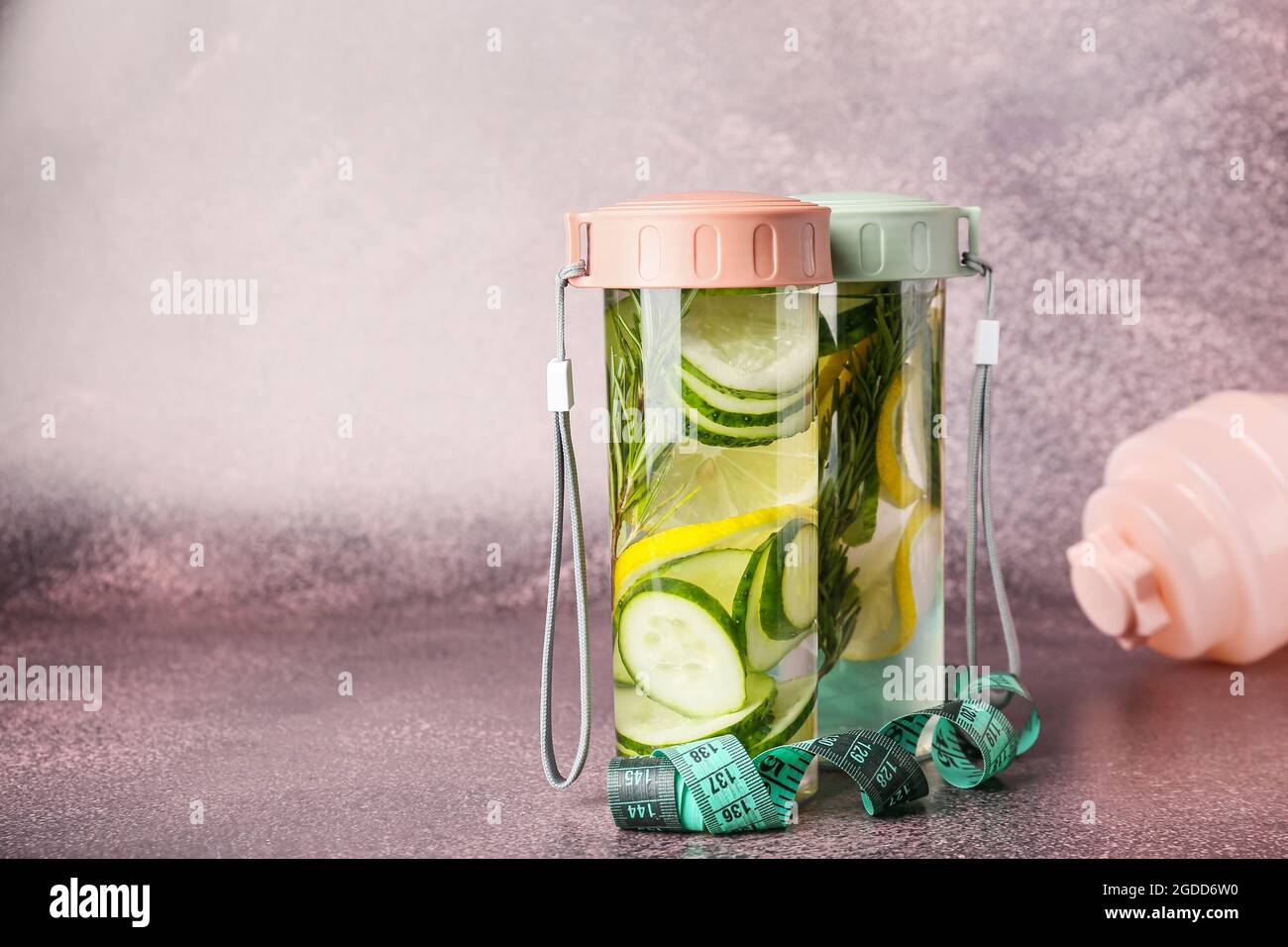 Bottles with cucumber lemonade and measuring tape on grunge background ...