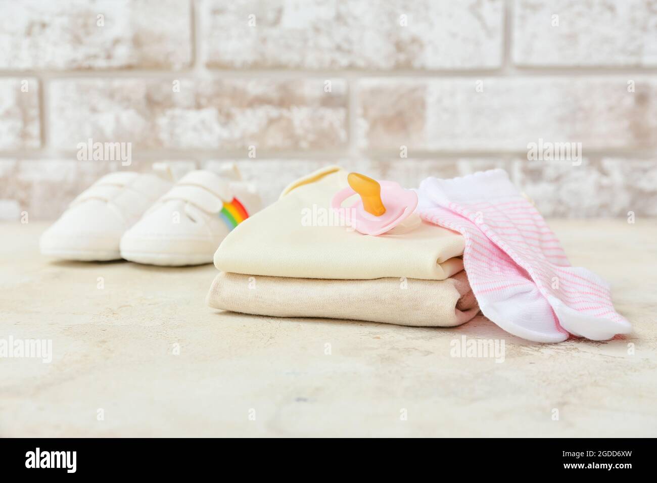 Set of baby clothes and accessories on table against brick wall Stock ...