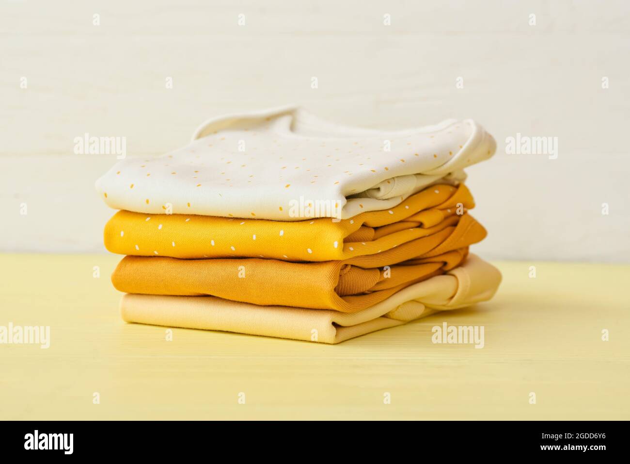 Stack of baby clothes on light wooden background Stock Photo - Alamy