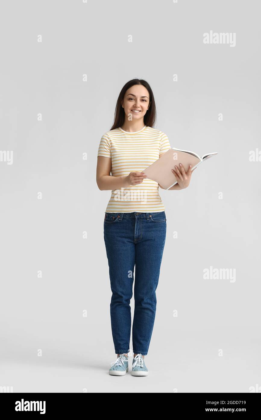 Beautiful young woman with magazine on grey background Stock Photo - Alamy