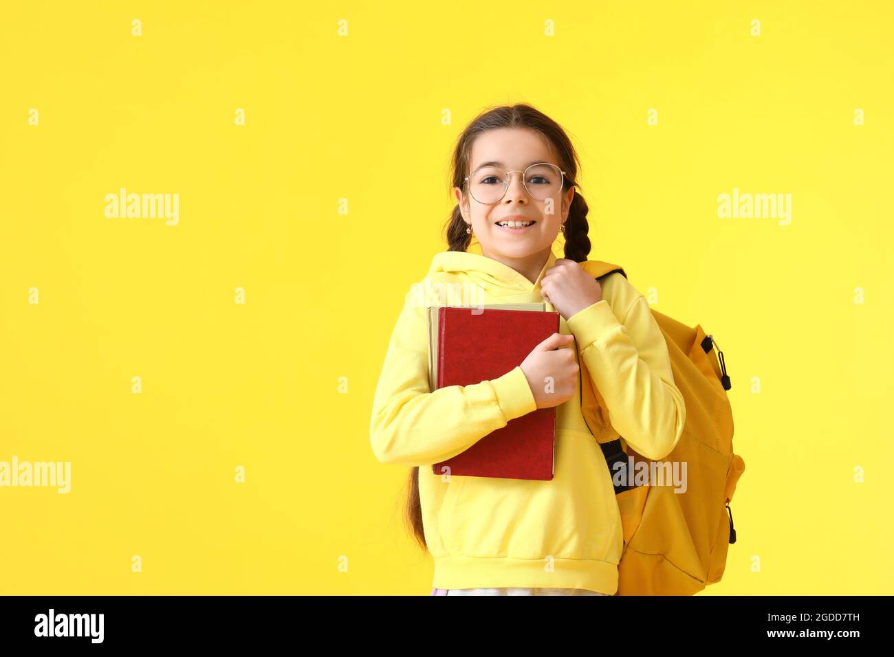 Happy little school girl with book on color background Stock Photo - Alamy