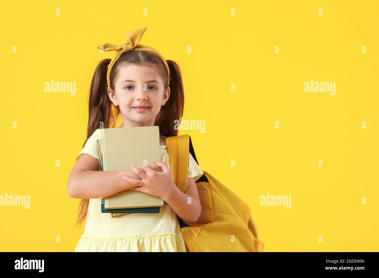 Cute little school girl with books on color background Stock Photo - Alamy