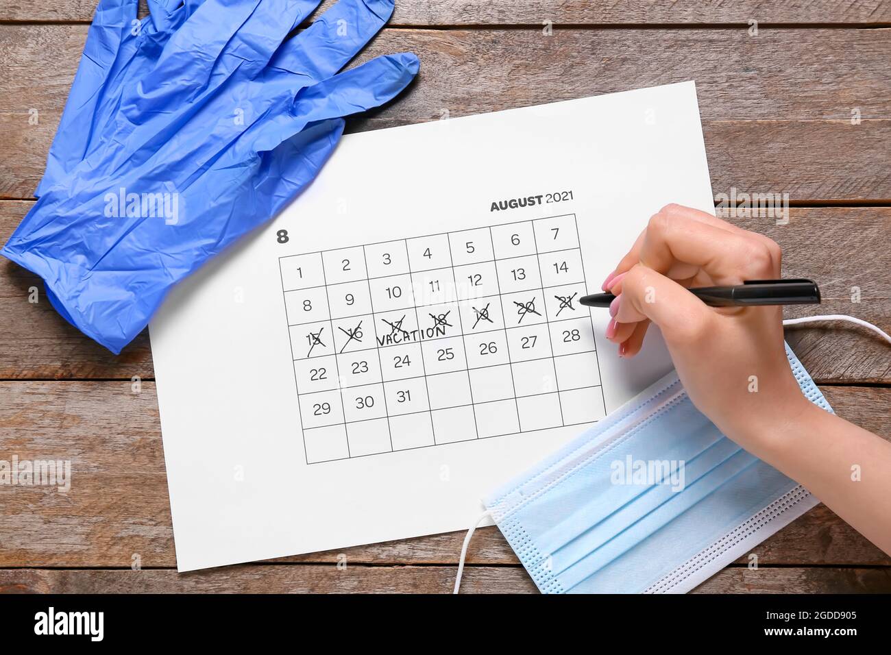 Woman marking dates in calendar on wooden background Stock Photo - Alamy