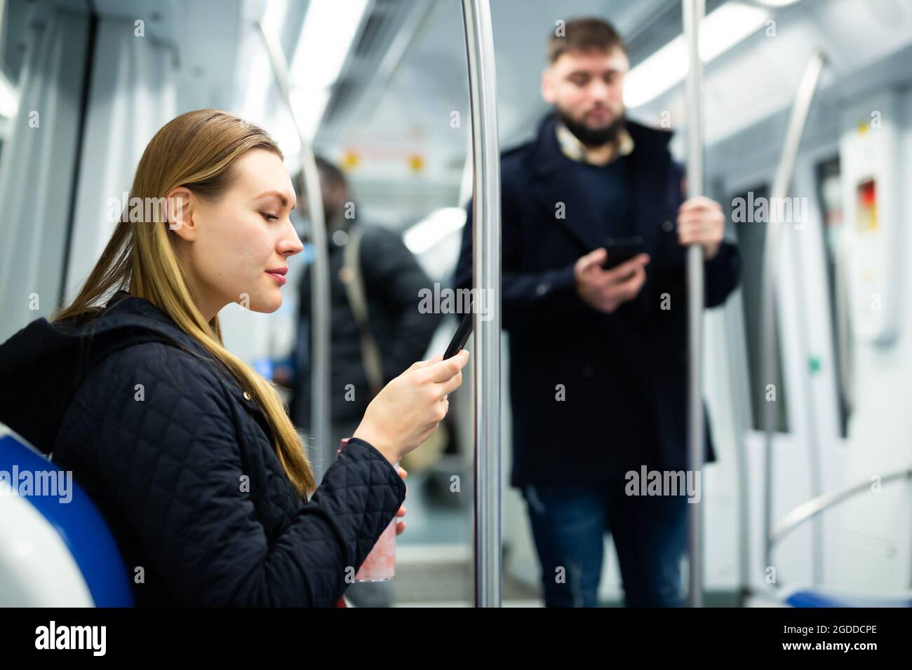 Girl using mobile phone in metro car Stock Photo - Alamy