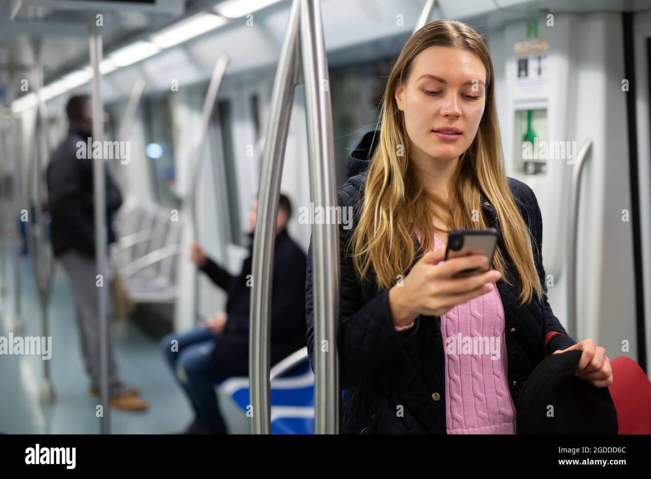 Girl using mobile phone in metro car Stock Photo - Alamy