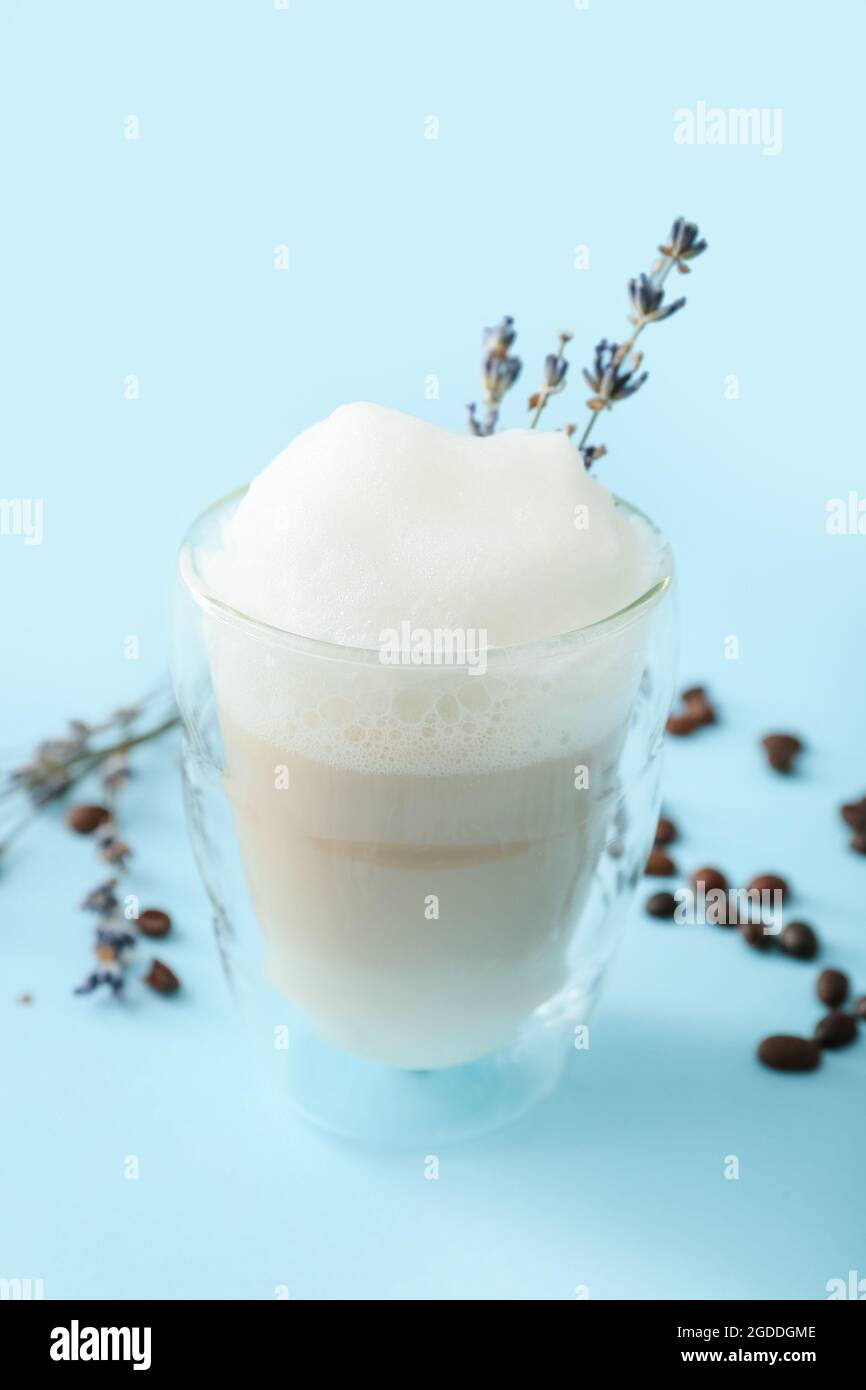 Glass of tasty lavender latte, coffee beans and flowers on color ...