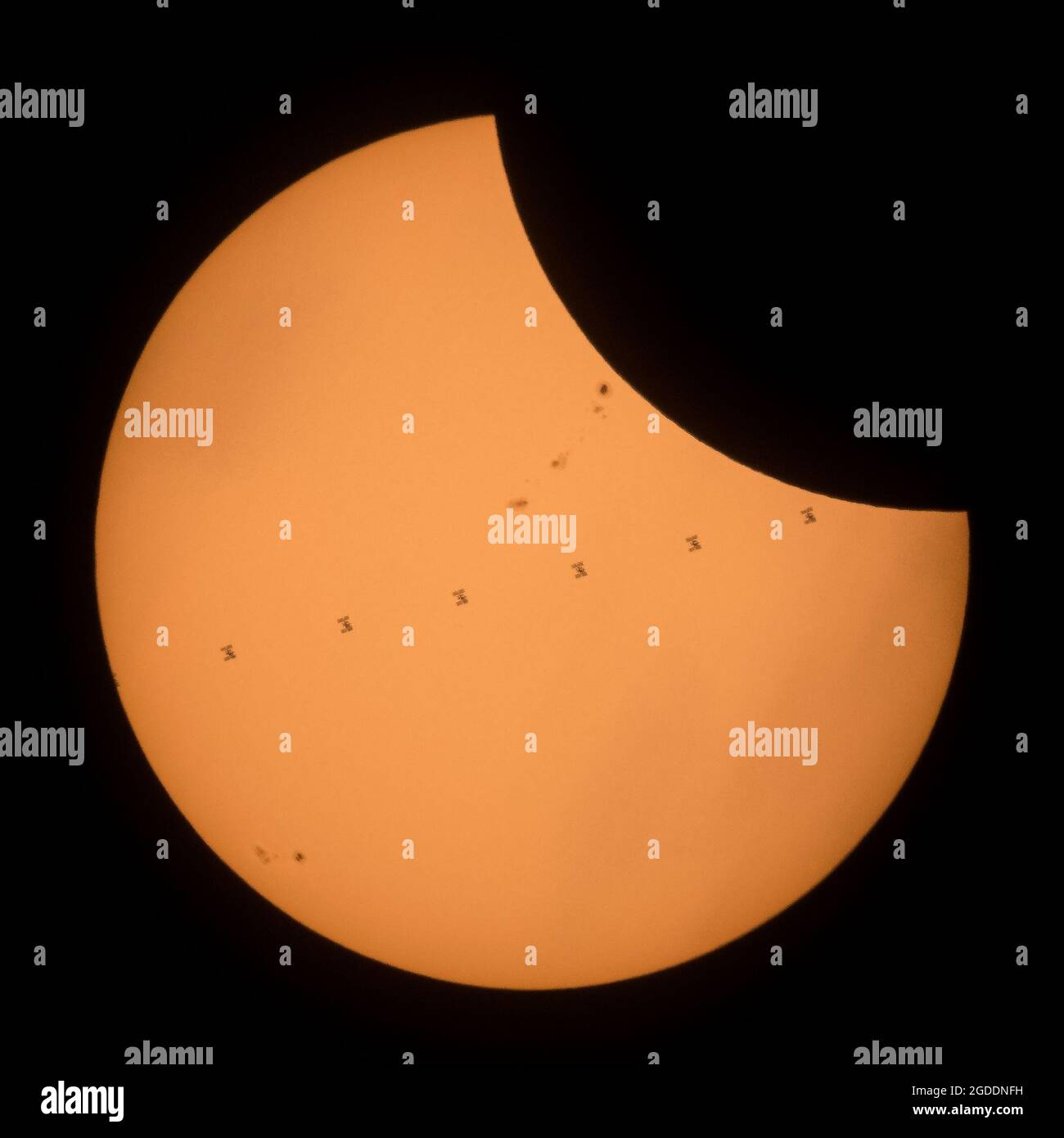 The International Space Station (ISS) passes in front of a partially ...