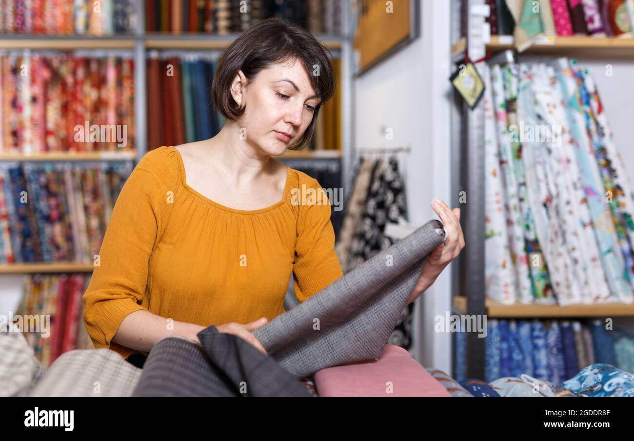 Woman choosing textiles in shop Stock Photo - Alamy