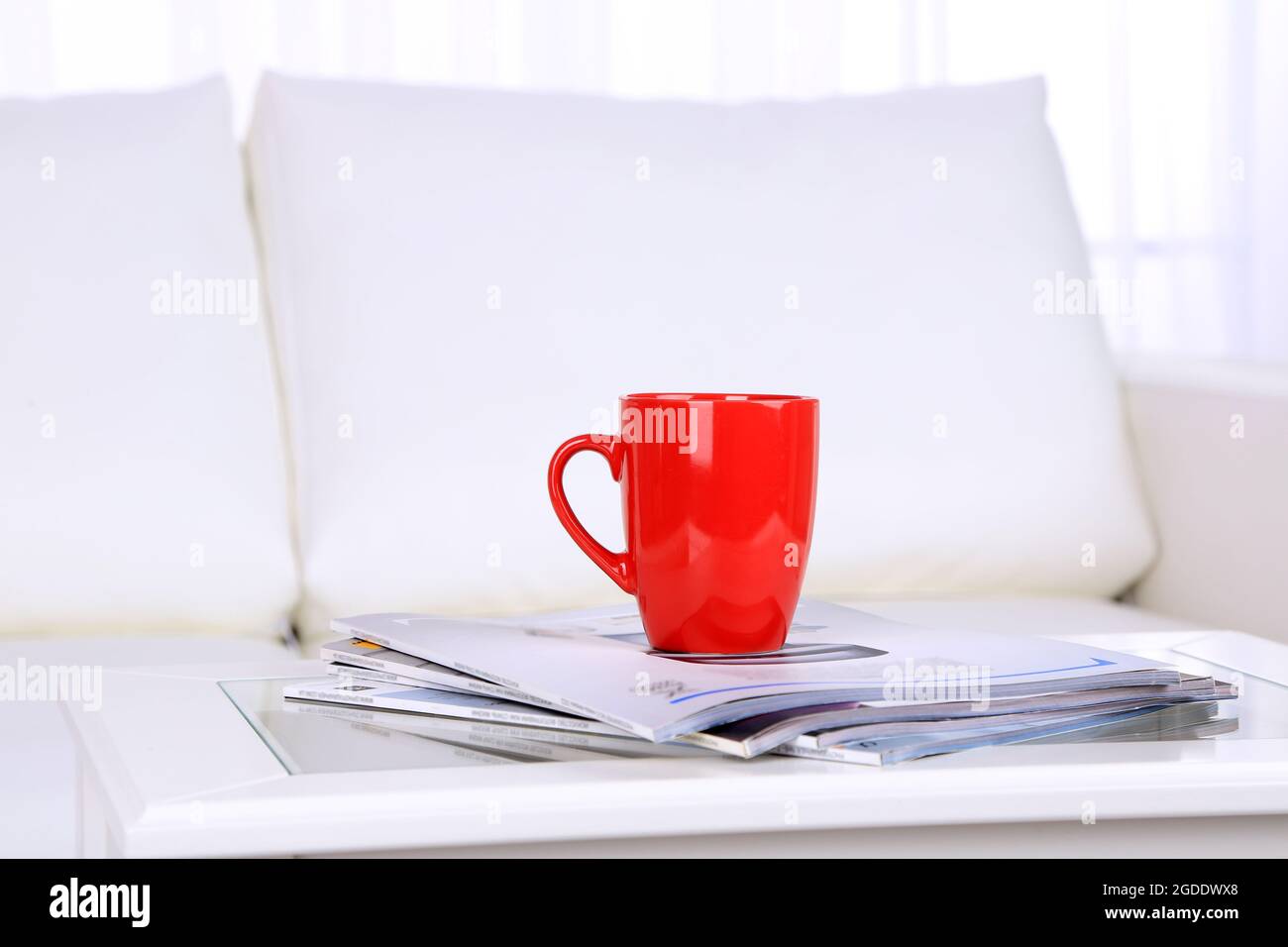 Magazines and cup on coffee table in room Stock Photo - Alamy