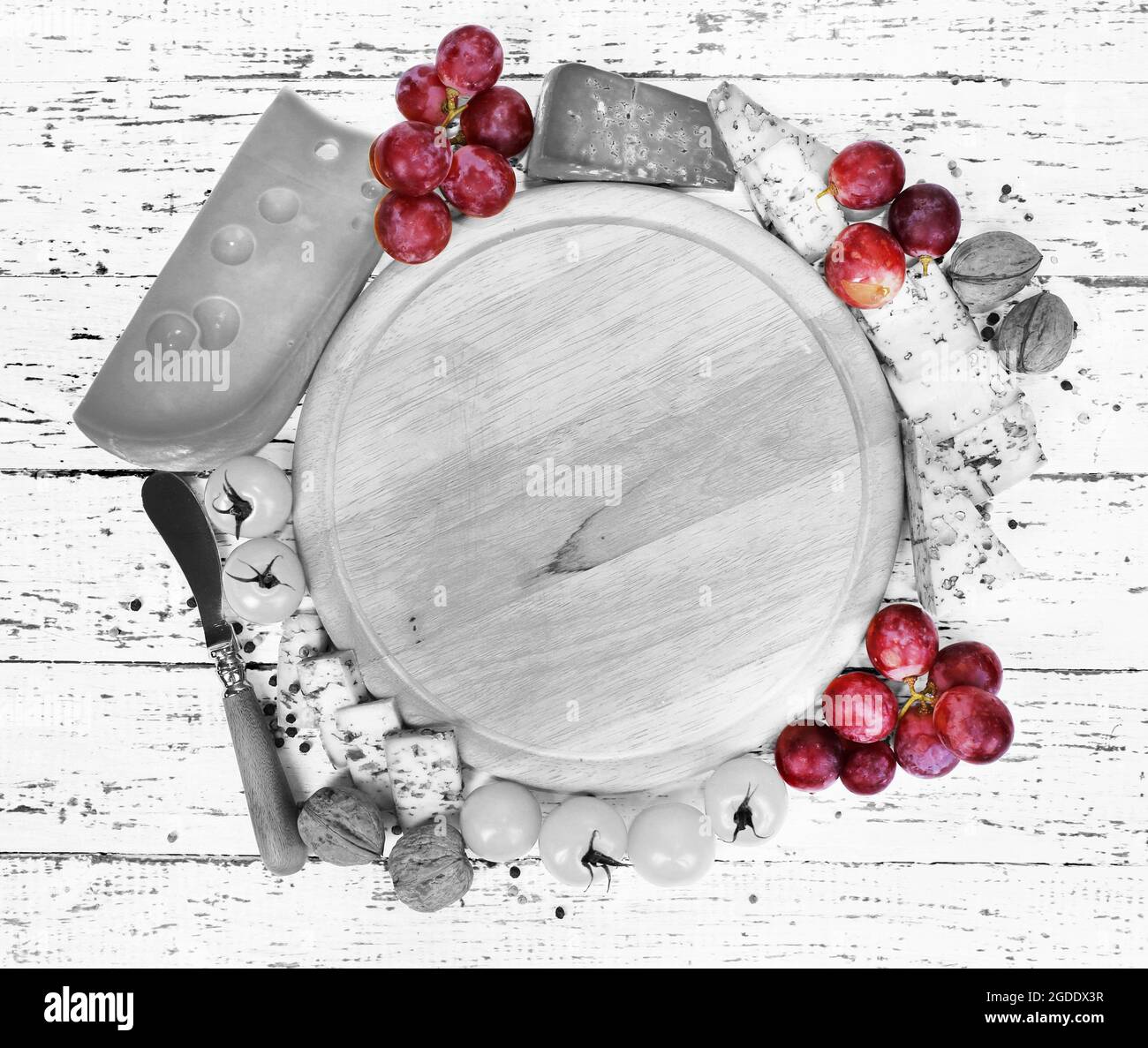Different types of cheese with empty board on table in shades of grey ...
