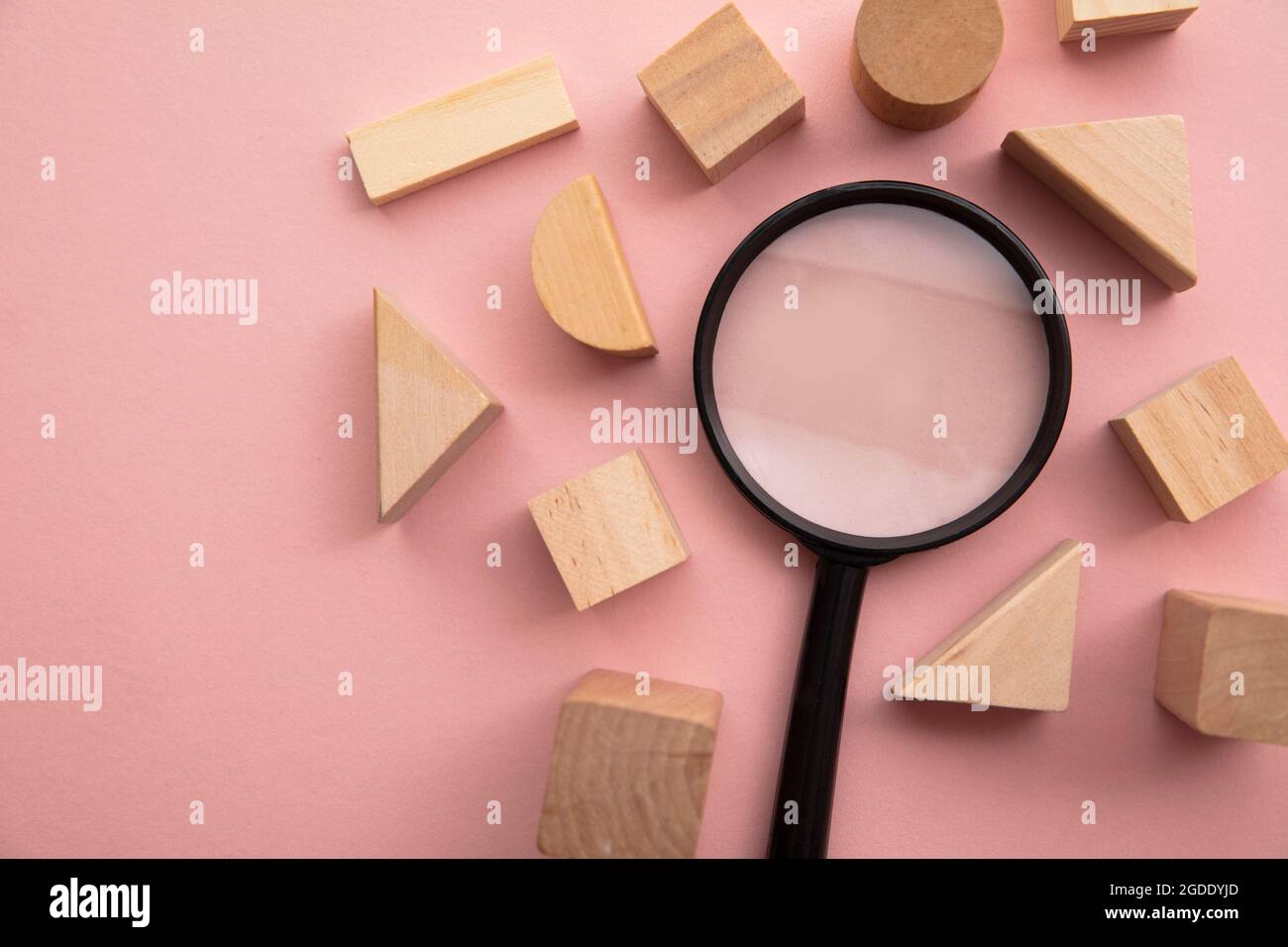 Magnifying glass with a selection of different shaped wooden blocks ...