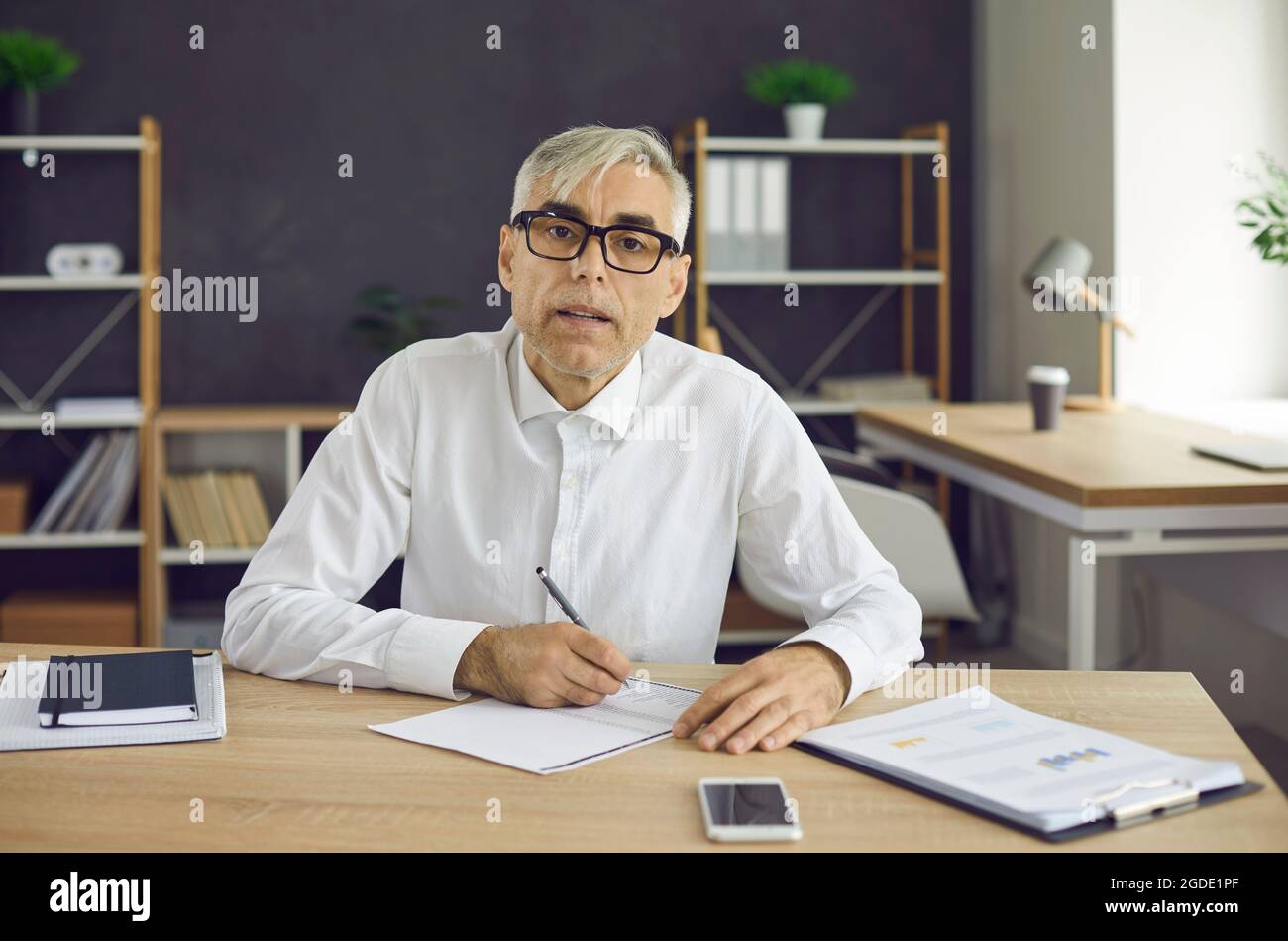 Focused senior business men take notes and write down important ...