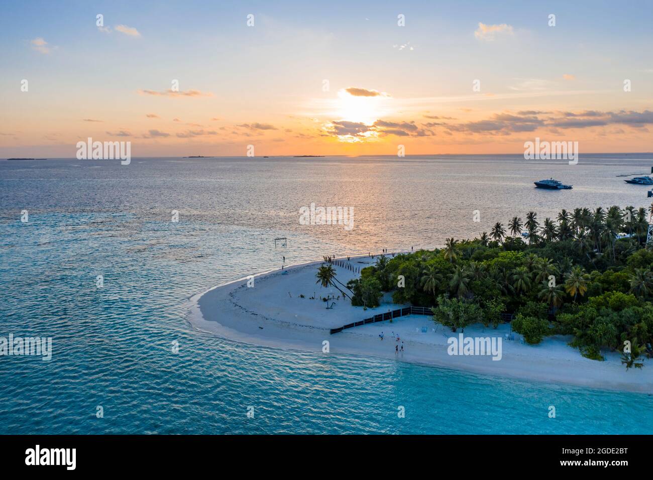 Aerial view of the sunset over a sandy island with palm trees and ...