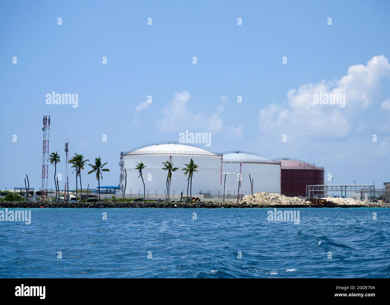 Palm trees, cell tower and huge fuel tanks on a Maldivian island in the ...