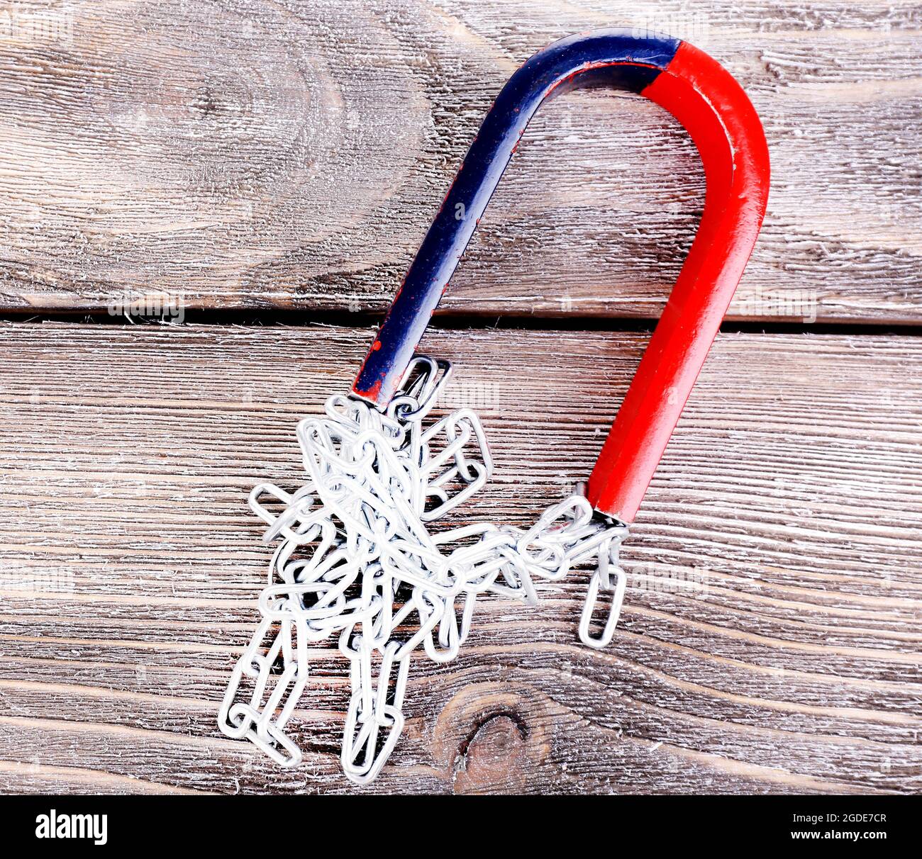 Magnet and chain on color wooden background Stock Photo - Alamy