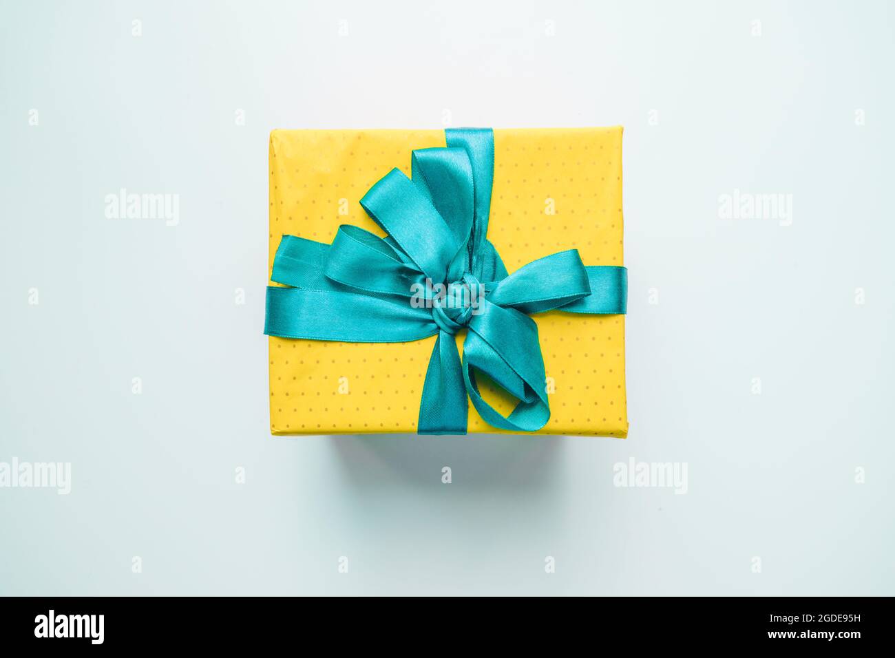 present gift box wrapped with yellow paper and blue ribbon top view ...