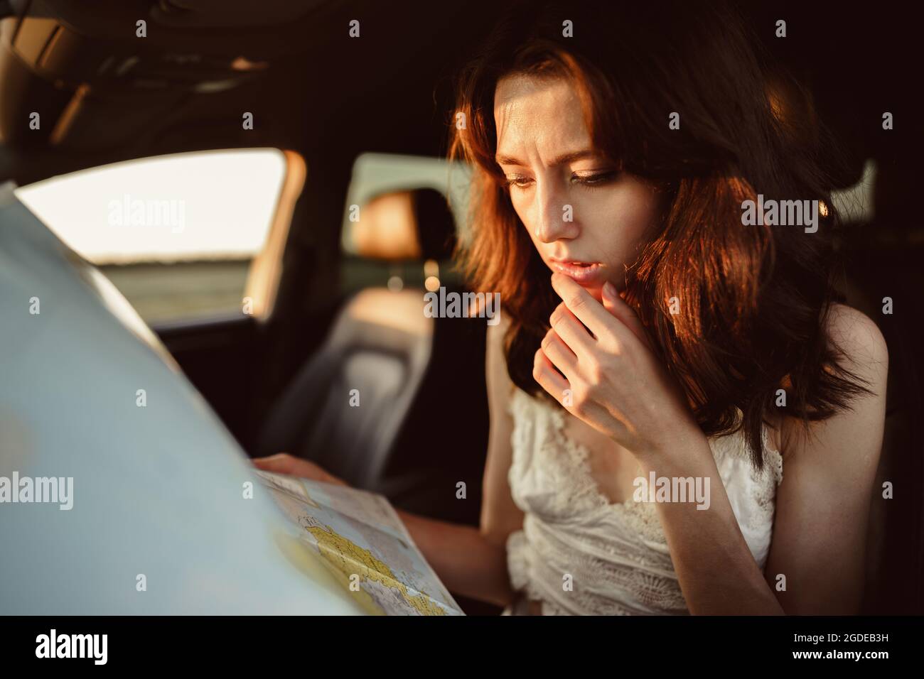 Lost young woman sitting in her car in the countryside and looking at ...