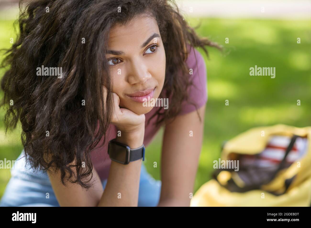 Long-haired pretty mulatta sitting on the bench with a thoughtful look ...