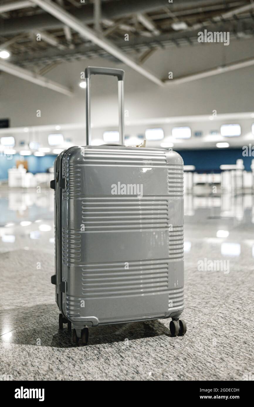 Gray travel suitcase in empty airport hall Stock Photo - Alamy