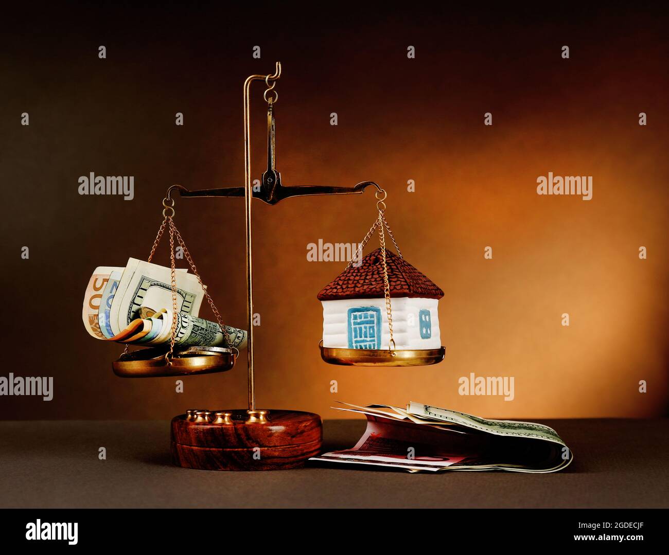 Scale with money and model of house on dark background Stock Photo - Alamy