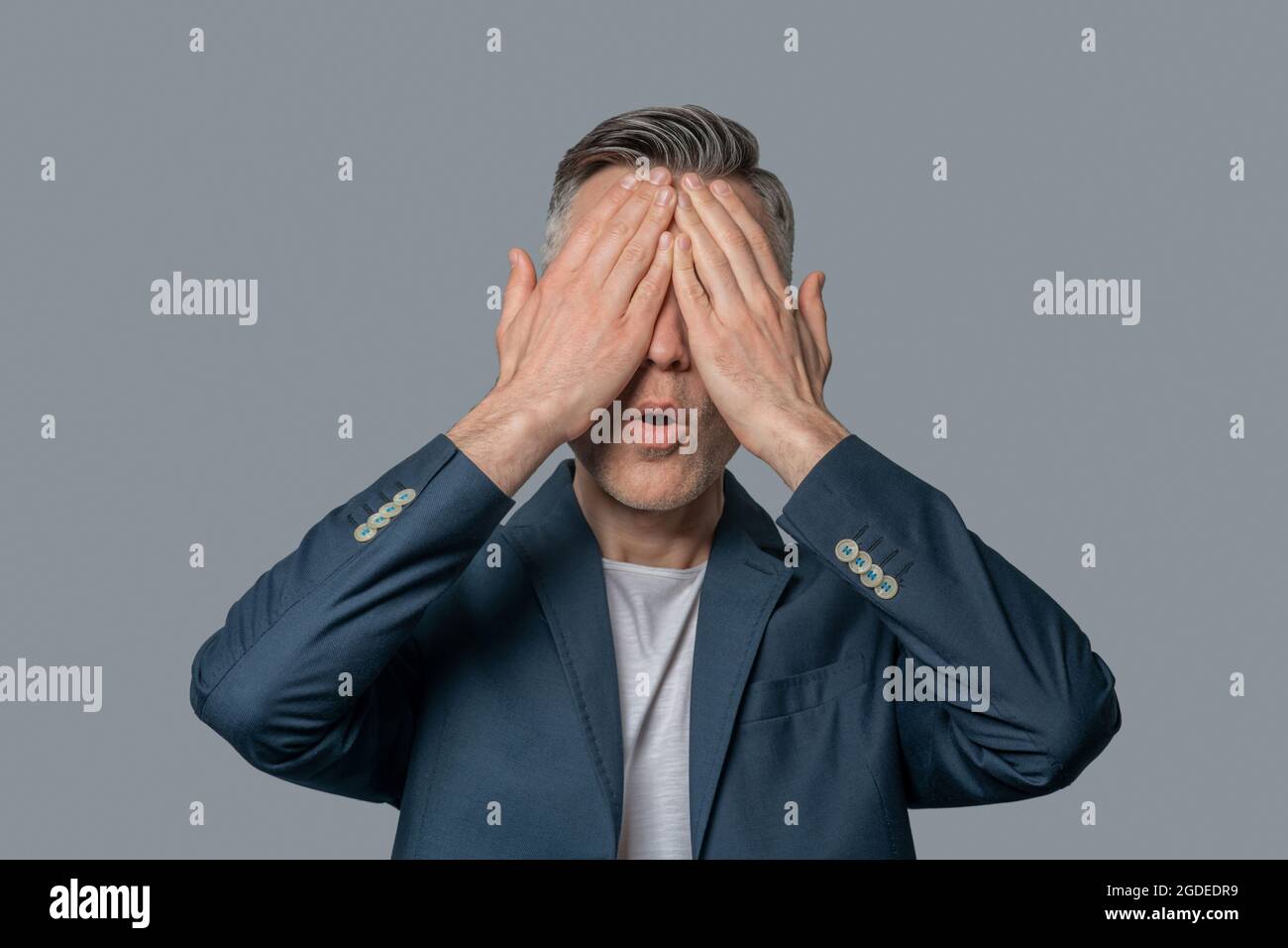 Man in jacket covering his face with palms Stock Photo - Alamy