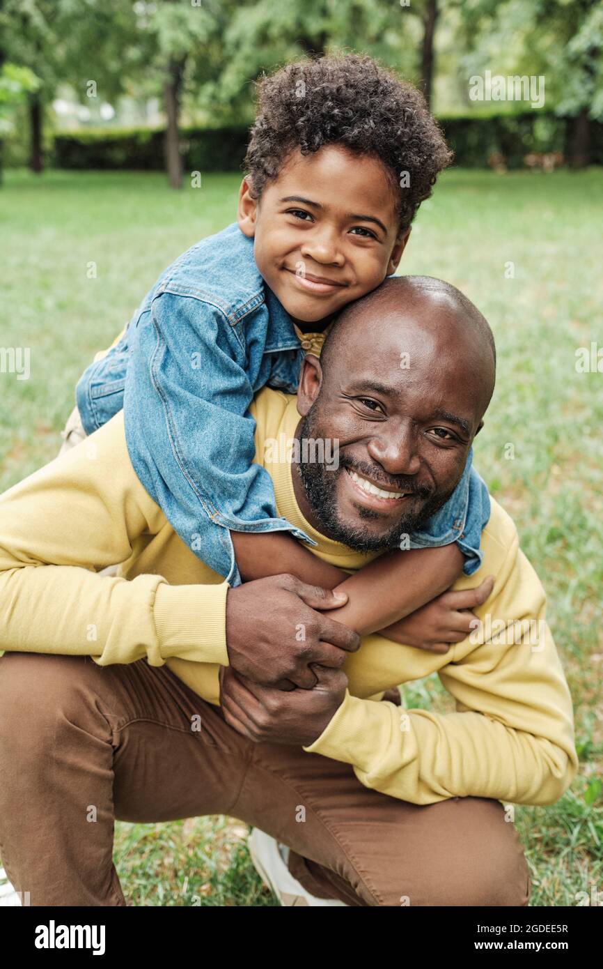 Portrait of happy African father smiling at camera while playing with ...