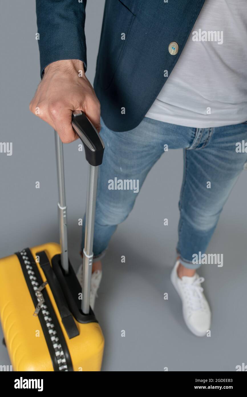 Man holding handle of travel suitcase Stock Photo - Alamy
