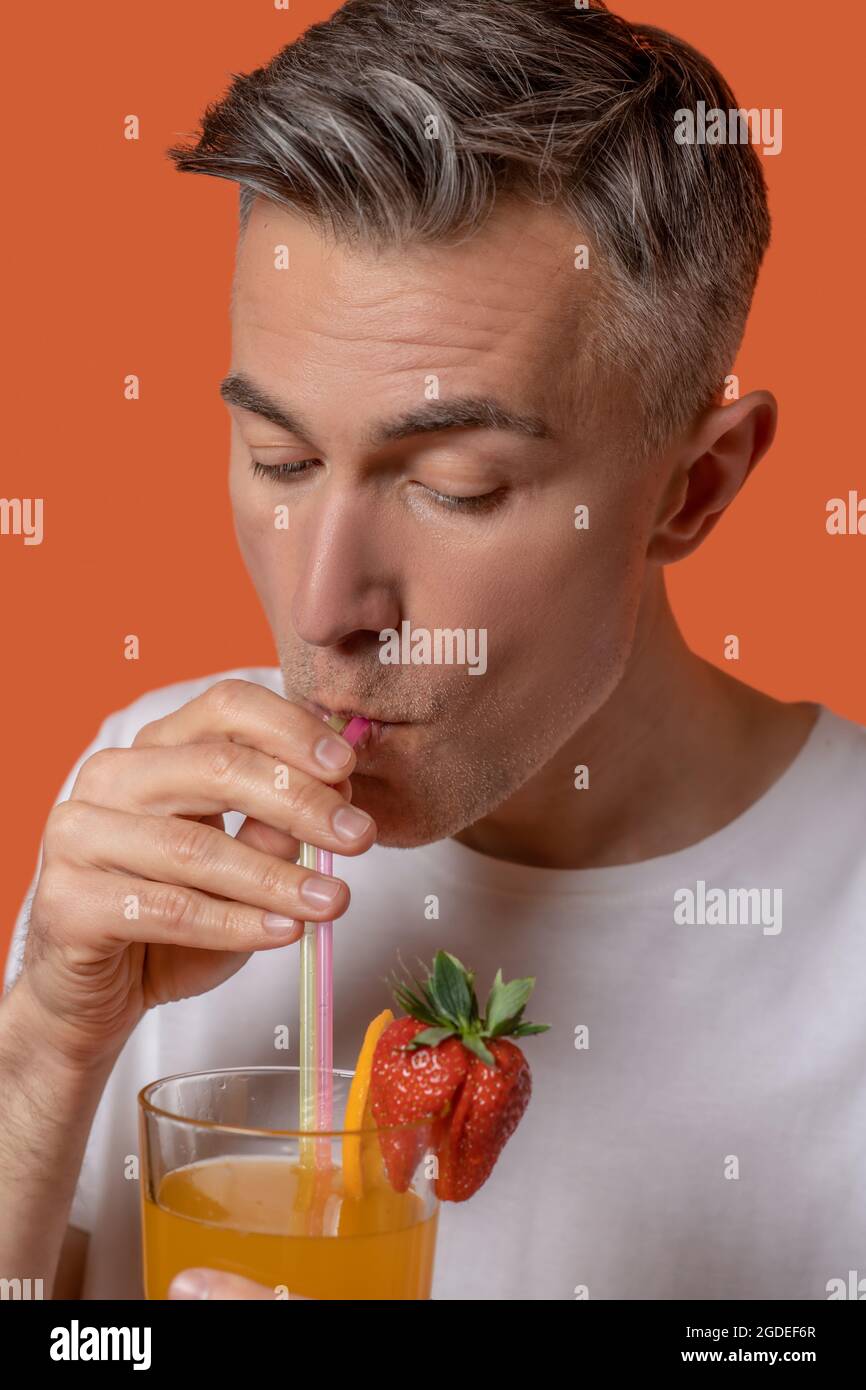 Concentrated man with drooping eyelids drinking fresh juice Stock Photo ...