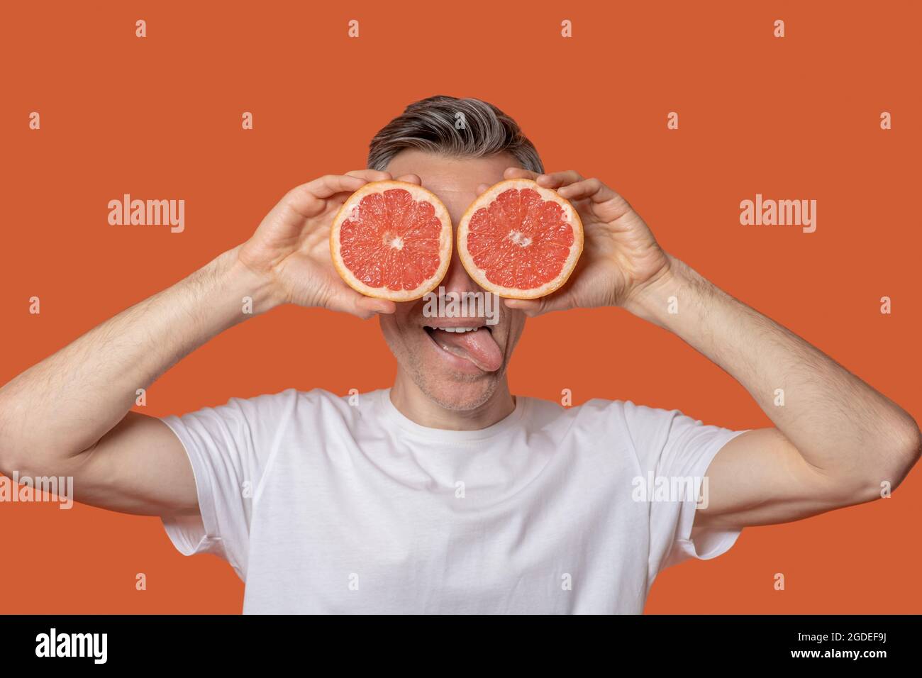 Man holding halves of grapefruit at eye level Stock Photo - Alamy