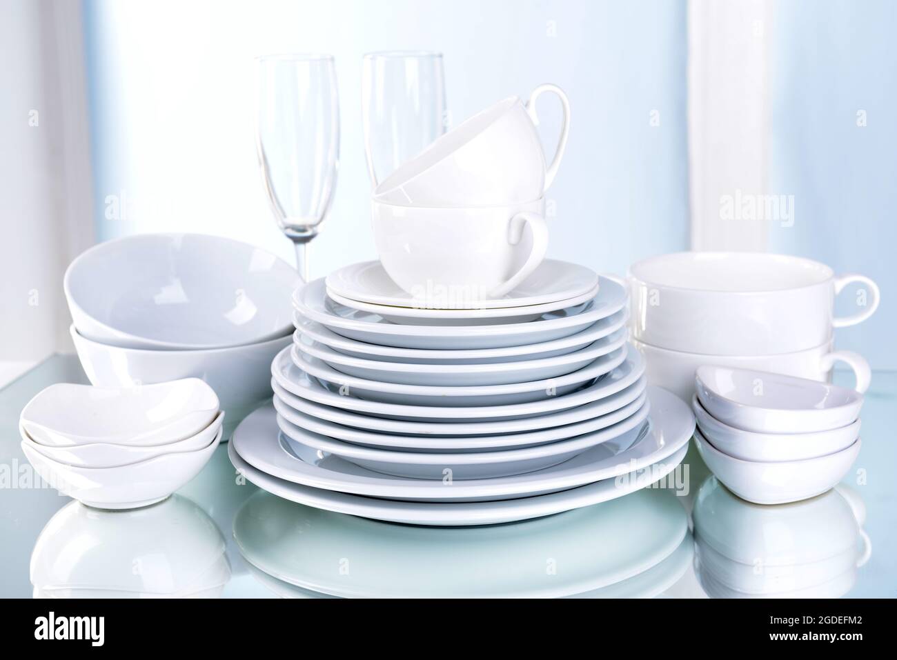 Set of white dishes on table on light background Stock Photo - Alamy