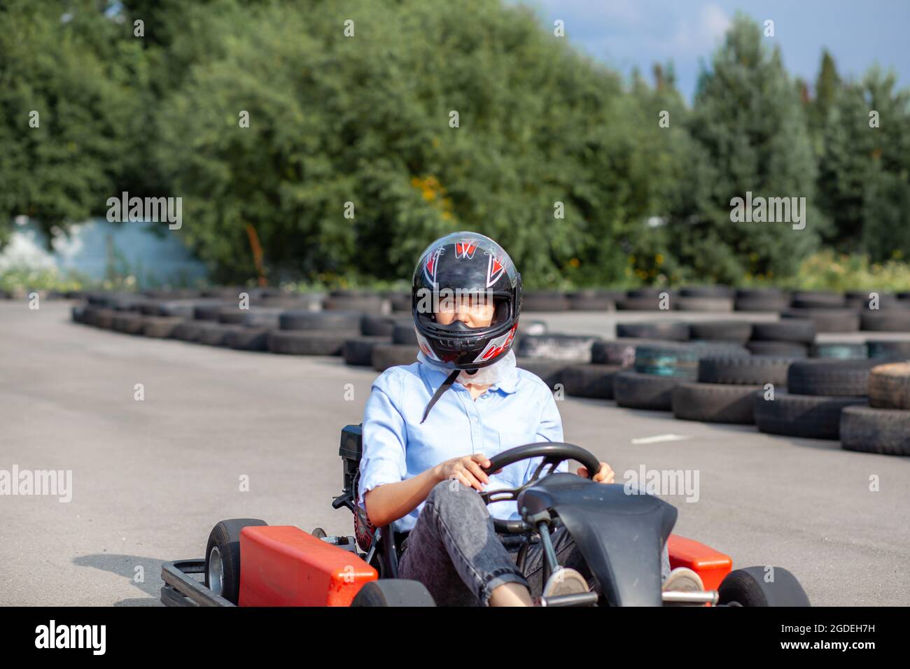 A girl or a woman in a hard hat rides a go-kart on a special track ...