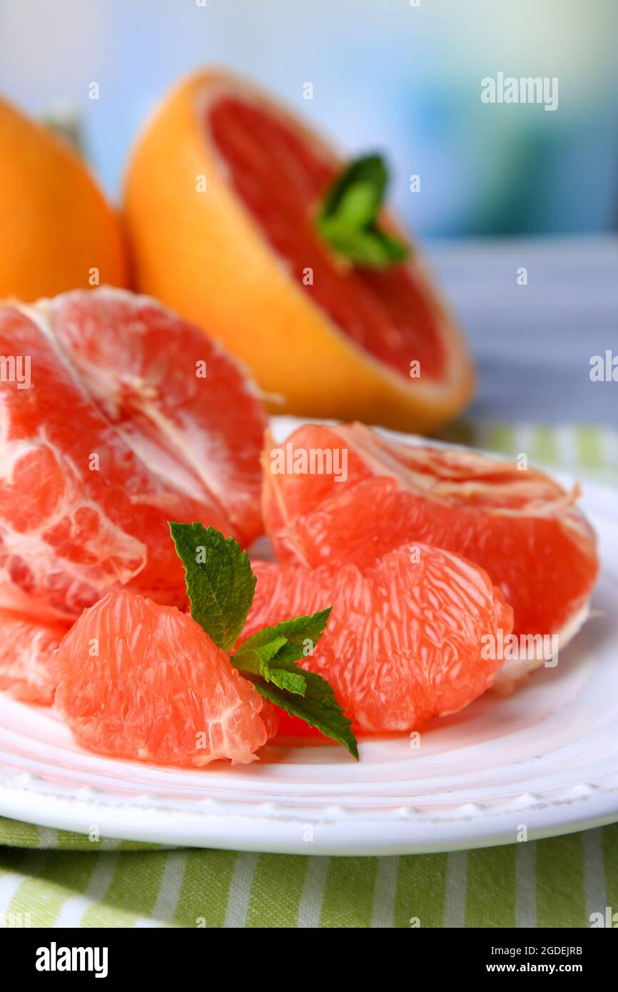 Ripe peeled grapefruits on plate, on color wooden background Stock ...