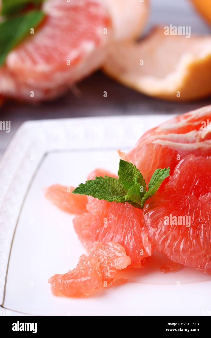 Ripe peeled grapefruits on plate, on color wooden background Stock ...