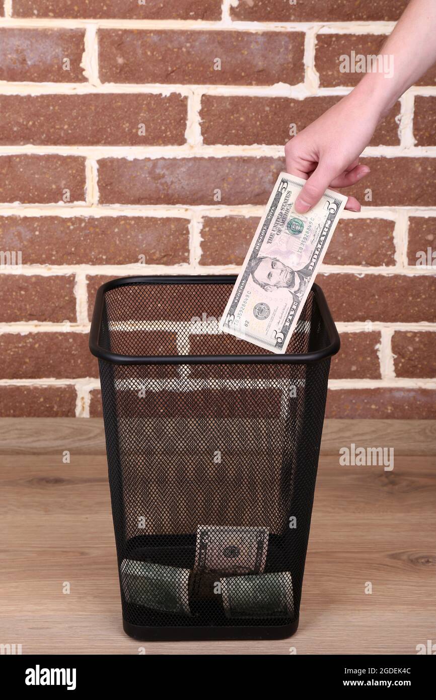 Throwing away your money on brick wall background Stock Photo - Alamy