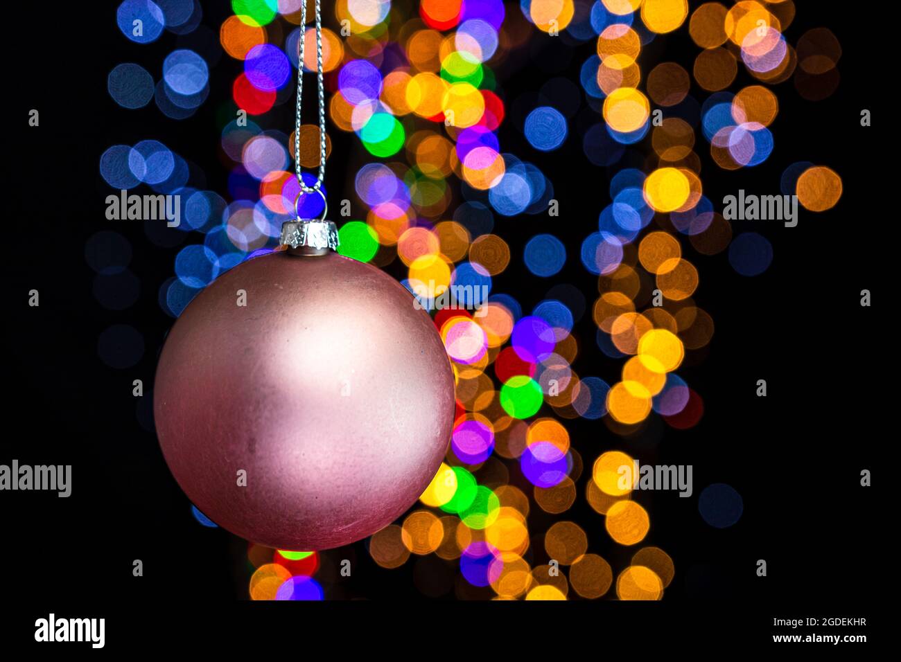 Hanging Christmas ball ornament against colorful bokeh lights ...