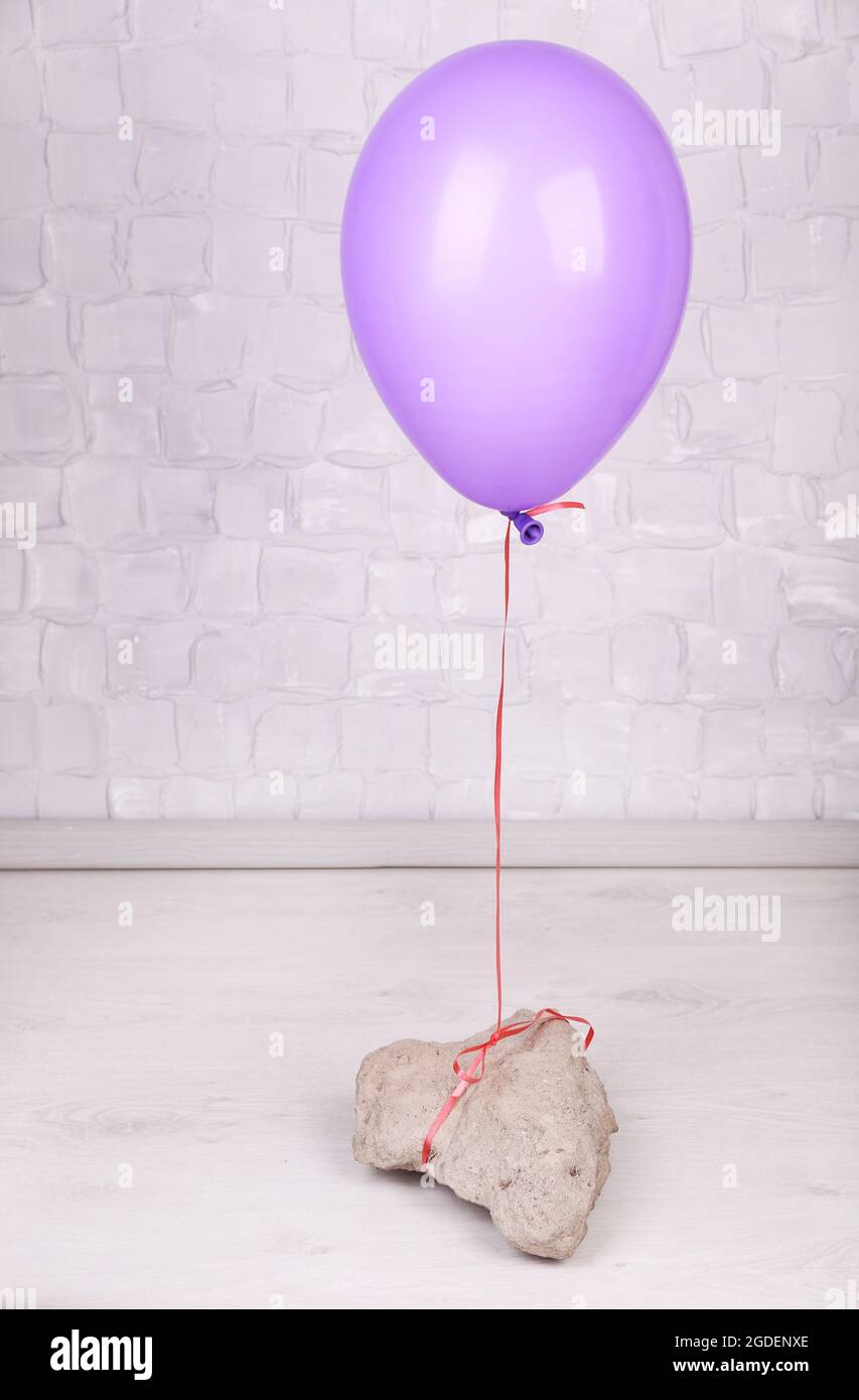 Color balloon with stone on grey wall background Stock Photo - Alamy