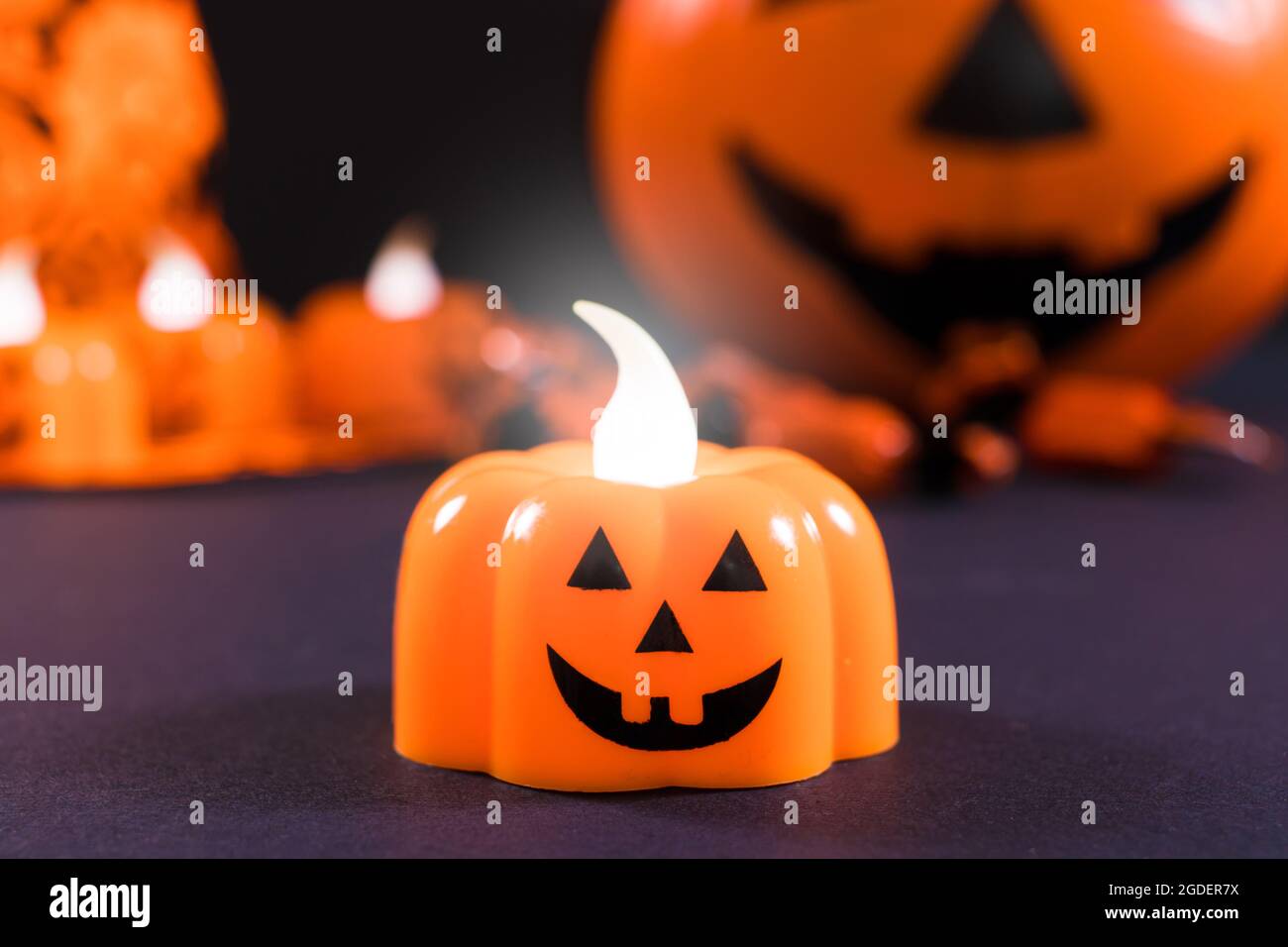Halloween card - a candle in the form of a pumpkin glows against a dark ...