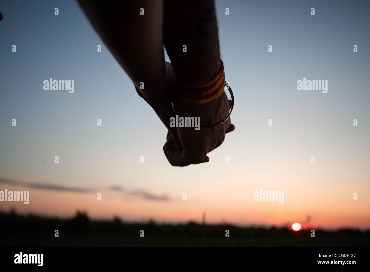 Romantic couple holding hands in summer field at sunset Stock Photo - Alamy