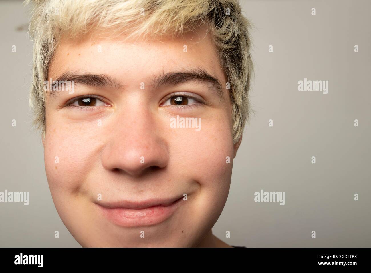 funny portrait of teenage boy close up with small smile on studio shoot ...