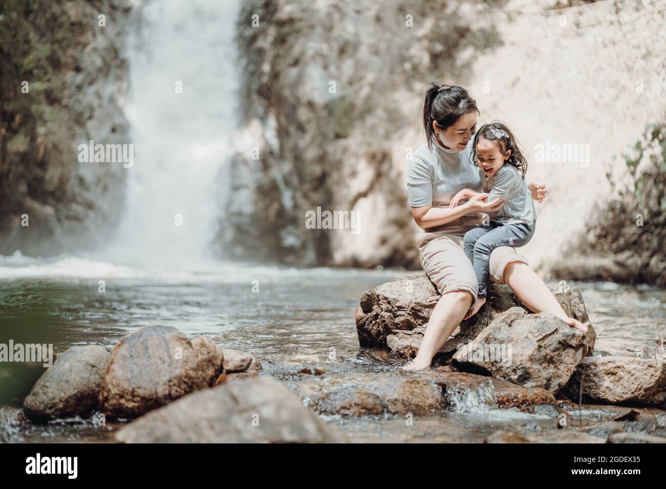 Mother and daughter sitting on the rocks in a forest Stock Photo - Alamy