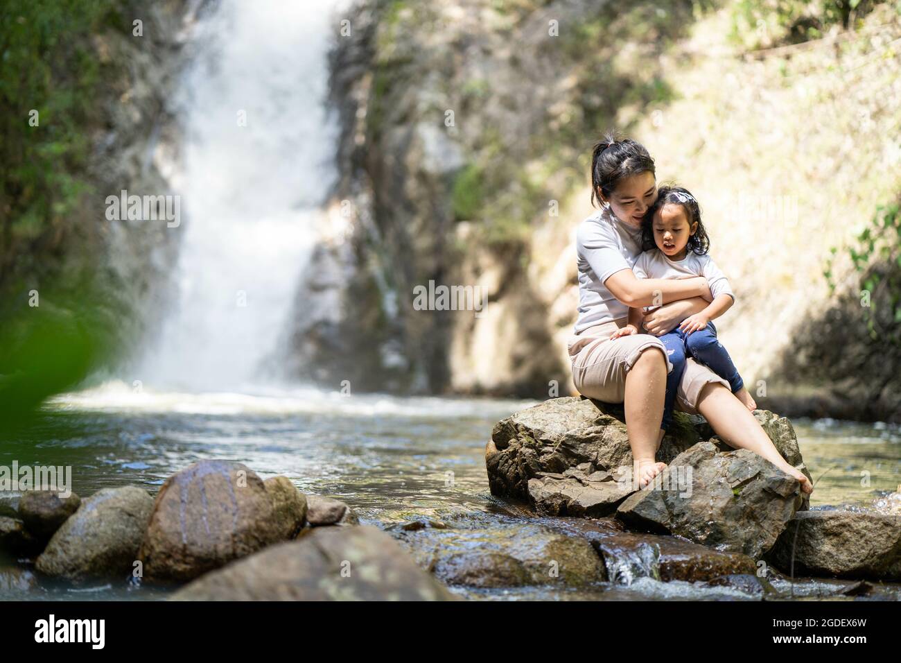 Mother and daughter sitting on the rocks in a forest Stock Photo - Alamy