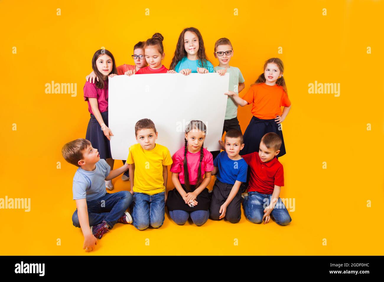 The group of kids holding a big white copy space poster Stock Photo - Alamy