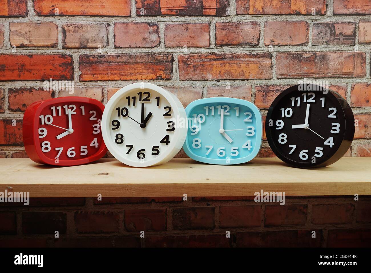 Clocks with time zone of different country on wooden shelves and brick ...