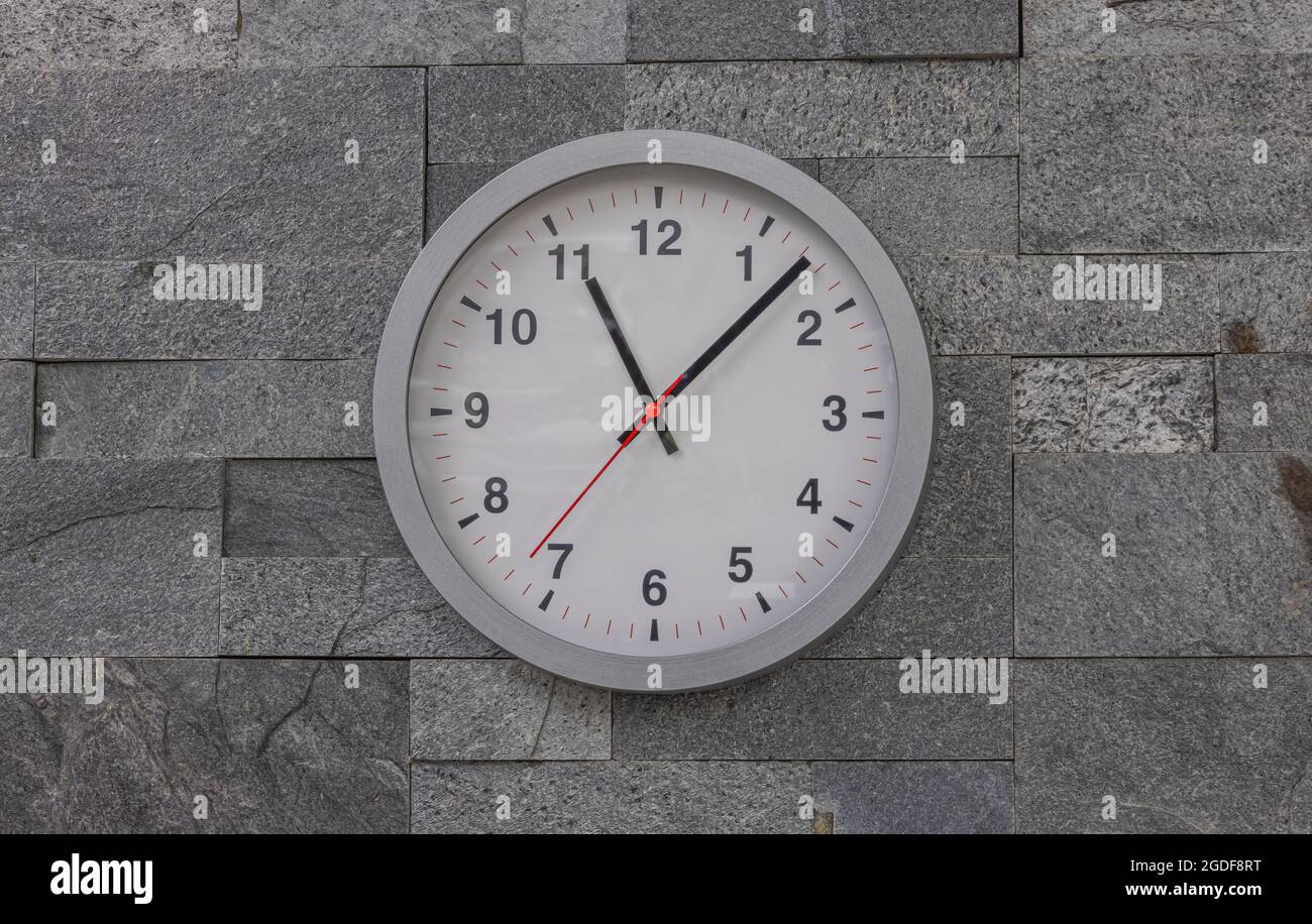 Modern wall clock on a wall tiled with rustic tiles. Modern white wall ...