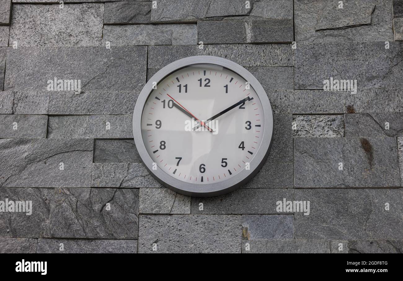 Modern wall clock on a wall tiled with rustic tiles. Modern white wall ...