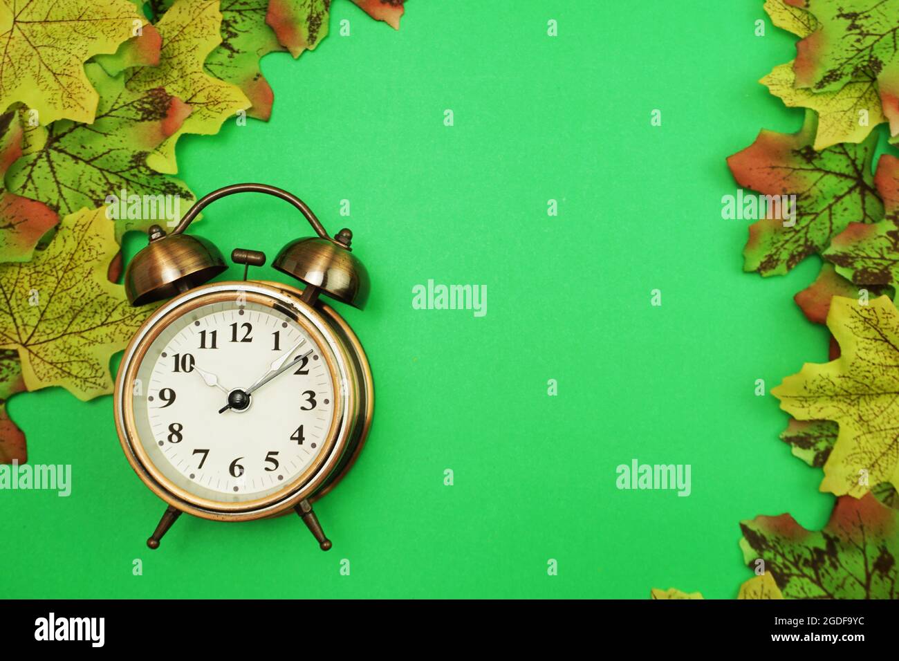 Alarm clock with Maple leaf border on green background Stock Photo - Alamy