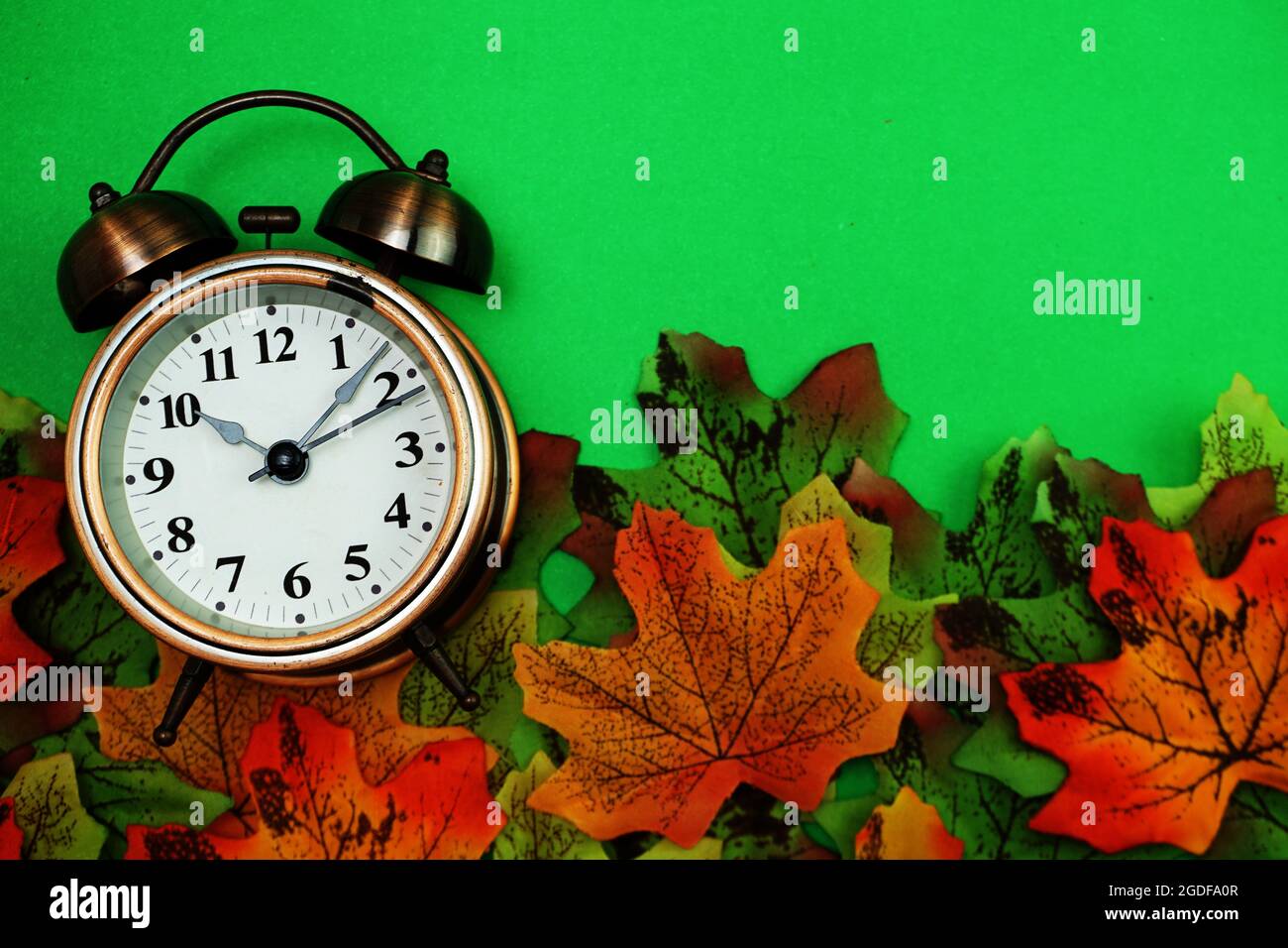 Alarm clock with Maple leaf border on green background Stock Photo - Alamy