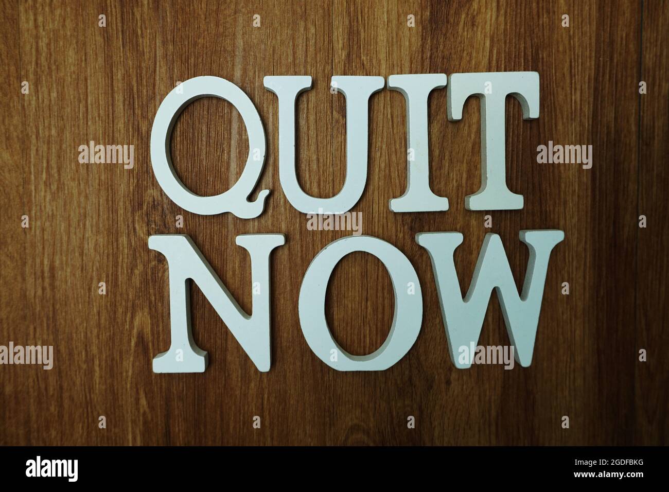Quit now alphabet letters on wooden background Stock Photo - Alamy
