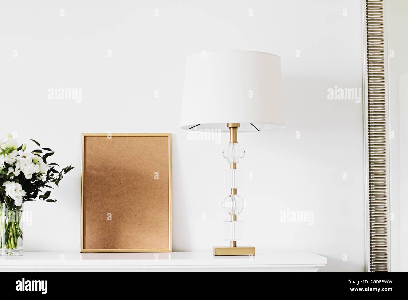 Golden vertical frame and bouquet of fresh flowers on white furniture ...